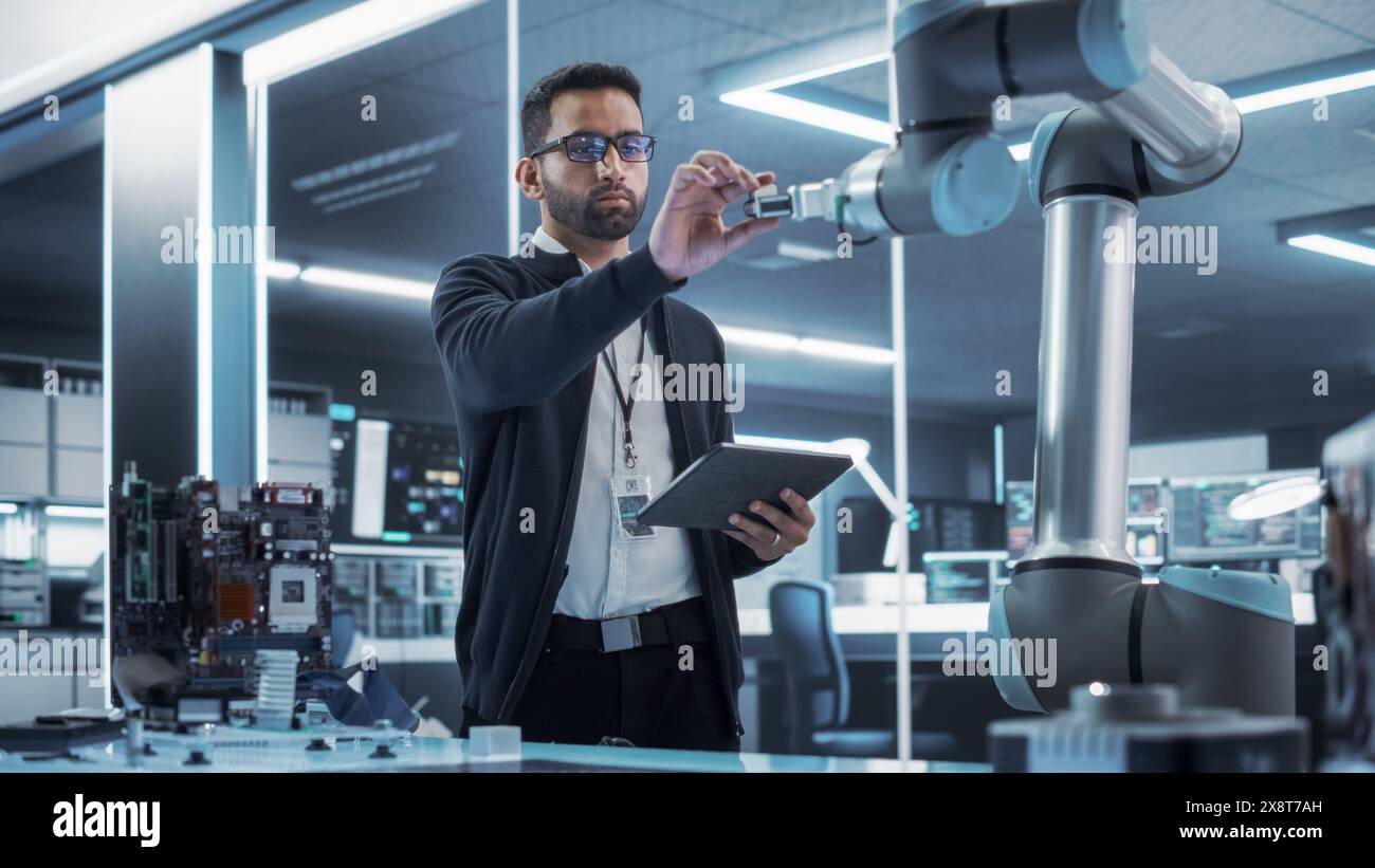 Portrait of a Young Multiethnic Male Engineer Using Tablet Computer. Interacting with a Robotic ...