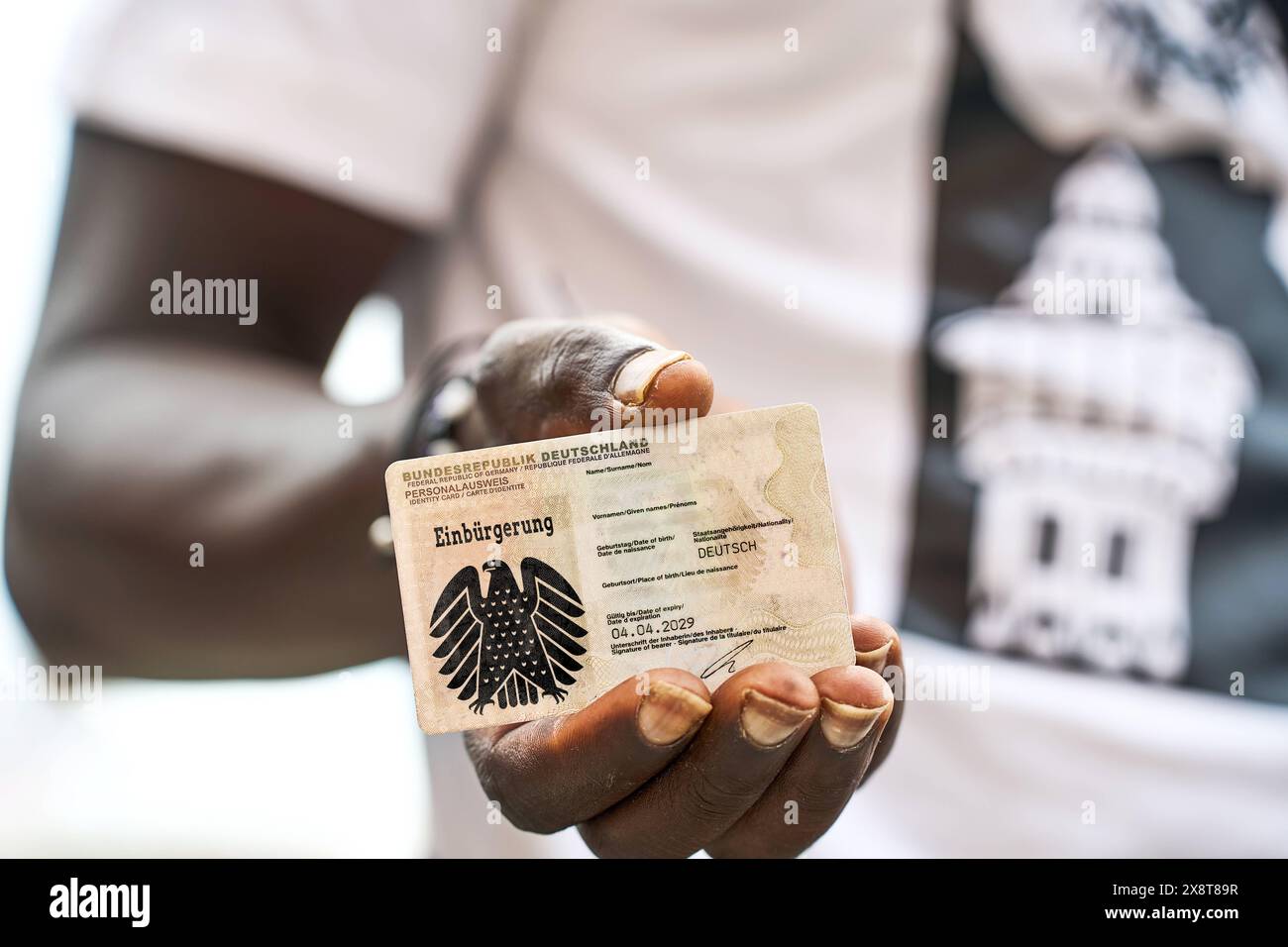 27 May 2024: Man holding a German identity card with the federal eagle ...