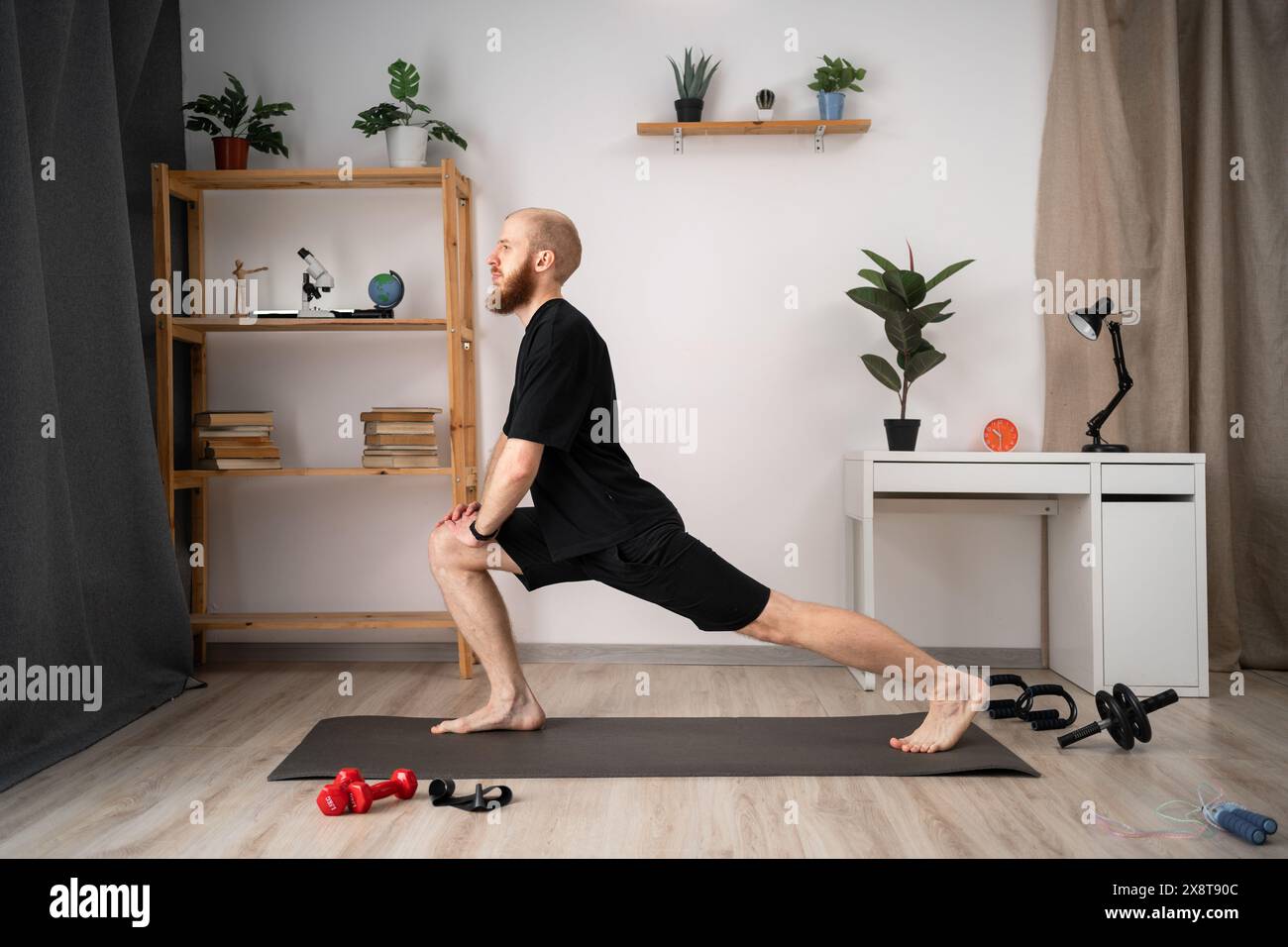 Athletic man doing forward lunge exercises at home in his apartment ...