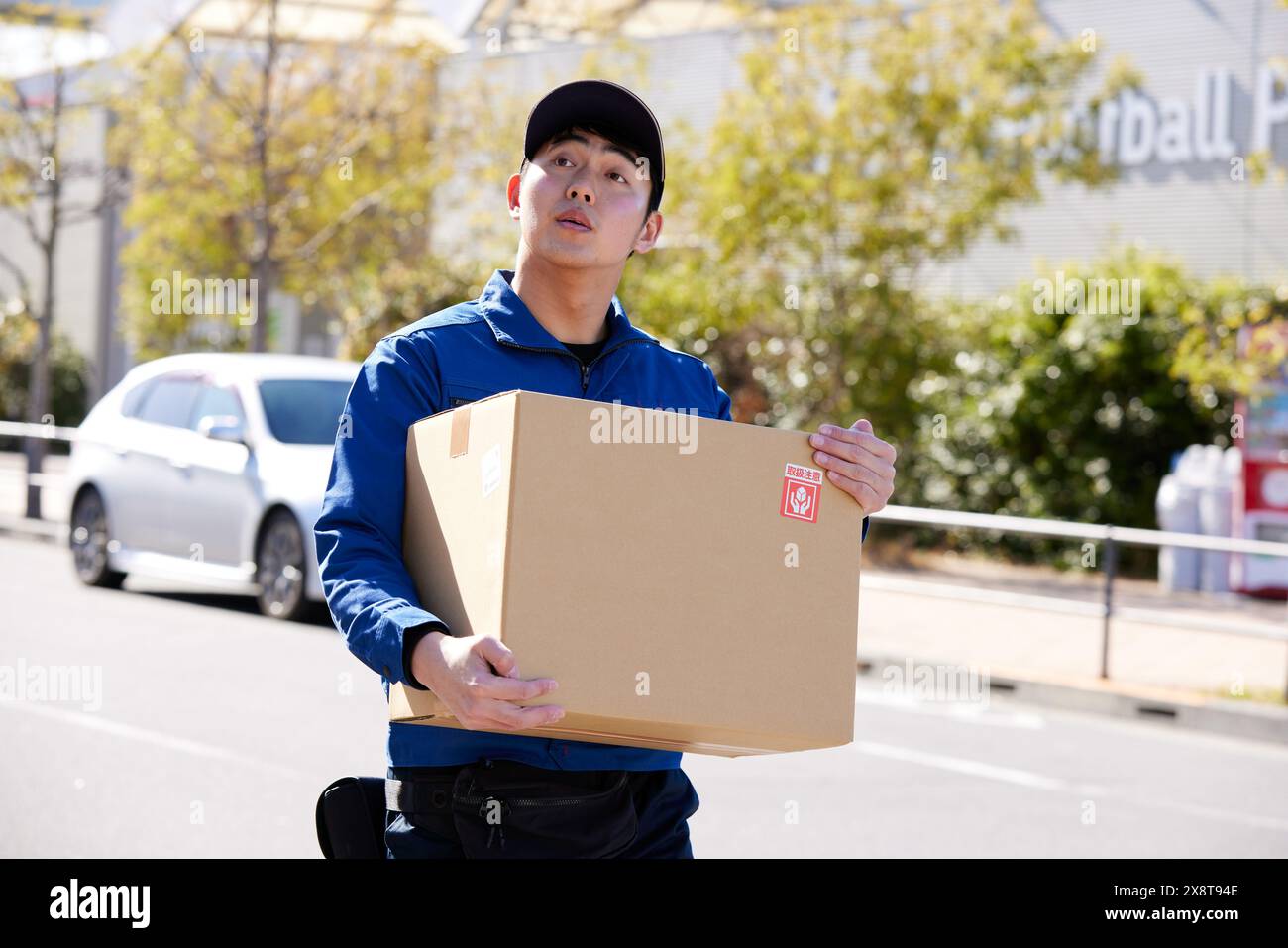 Japanese delivery man carrying a box on the street Stock Photo - Alamy