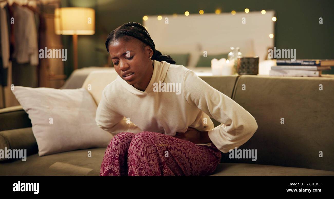 African woman, menstruation and stomach ache on sofa for pain, stress ...