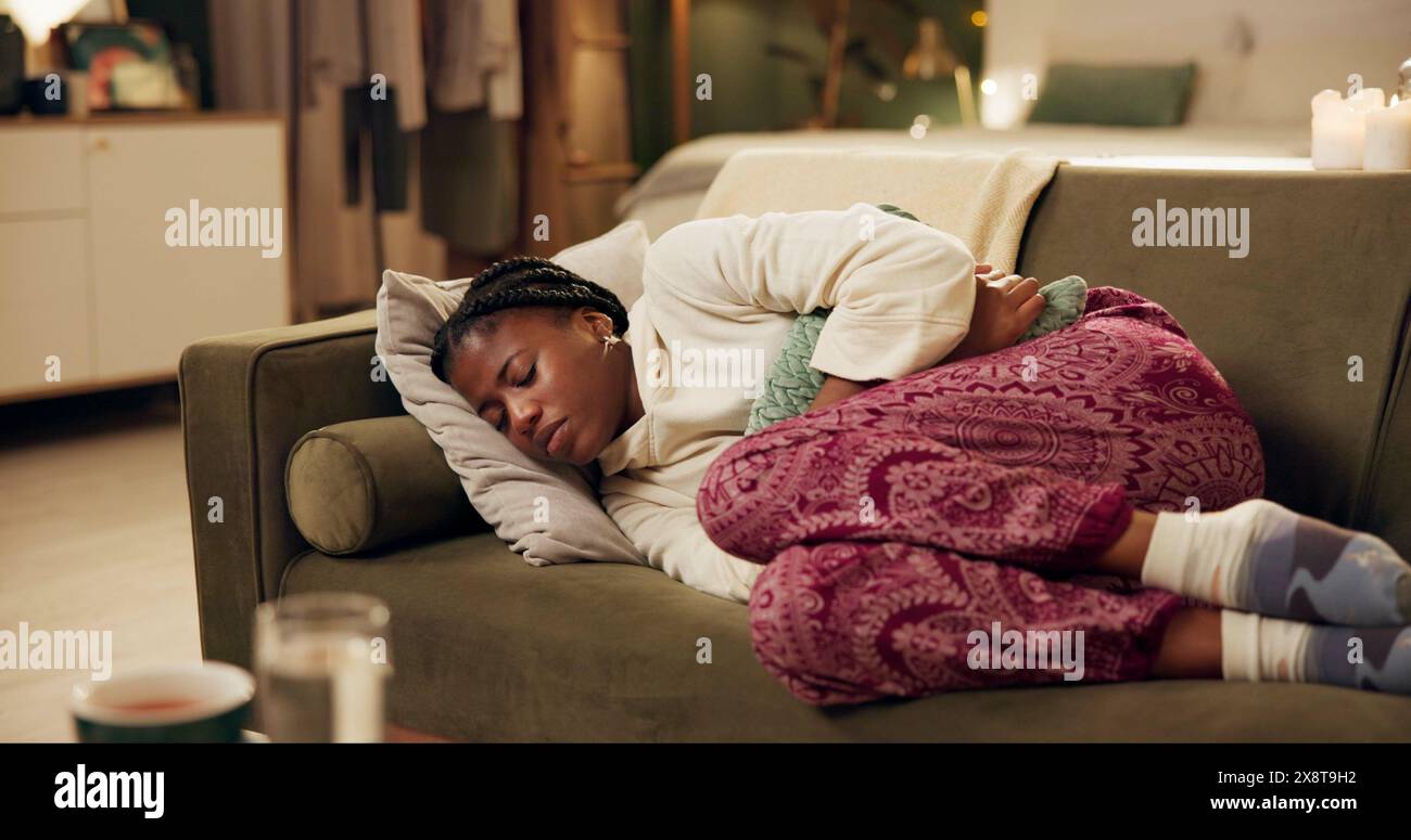 African woman, menstruation and stomach on couch with pain, stress and ...