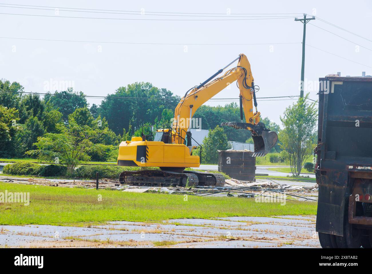 An excavator loads construction waste concrete into dump container ...