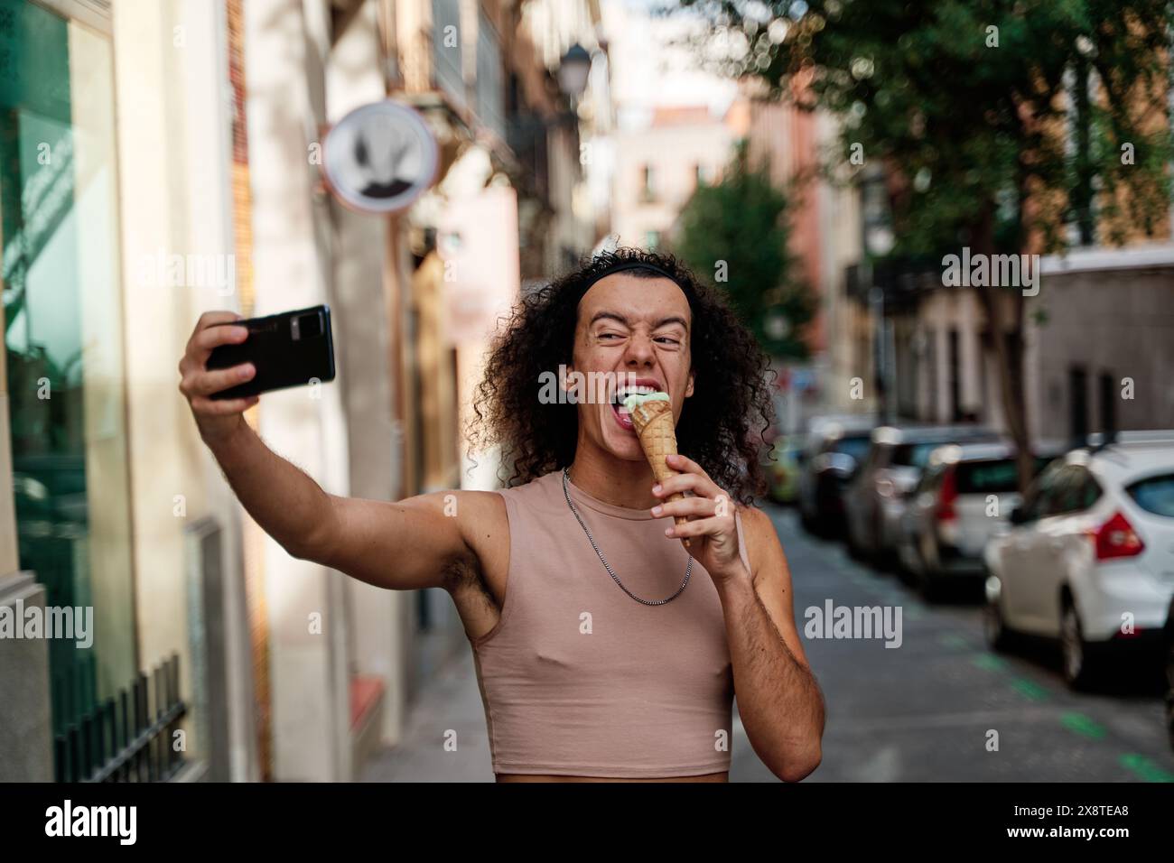 portrait of a young caucasian gay man with curly hair biting into an ...
