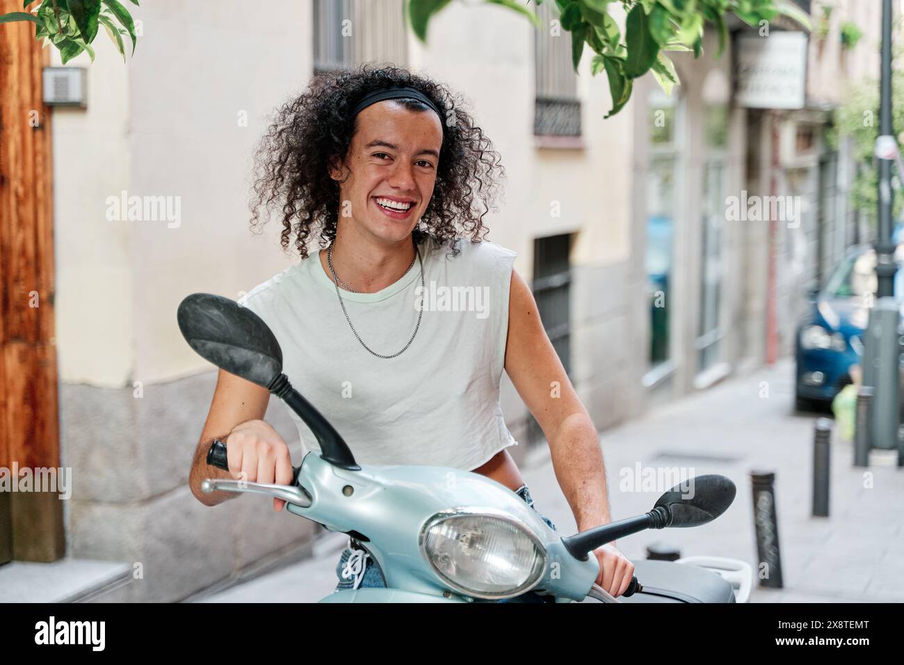 portrait of a man with curly hair getting on his motorcycle with a huge ...