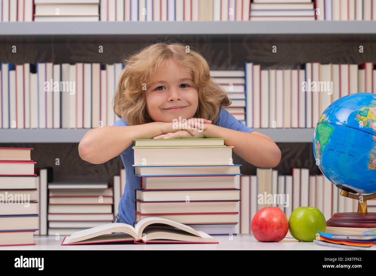 School boy with stack of books in library. Smart caucasian school boy ...