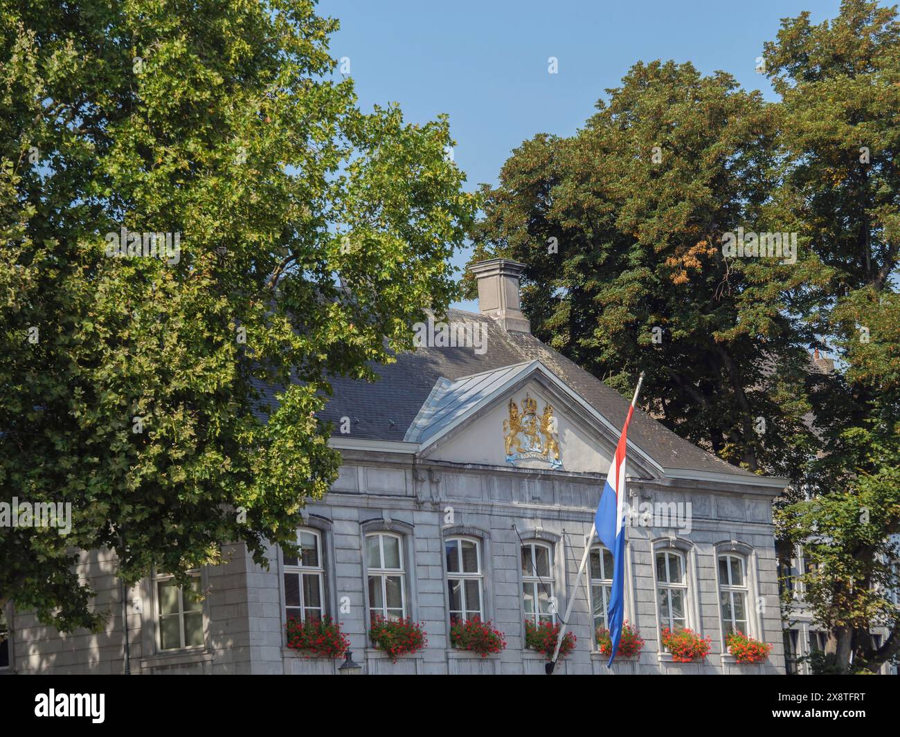 Historic building with Dutch flag, flower boxes and surrounding trees ...