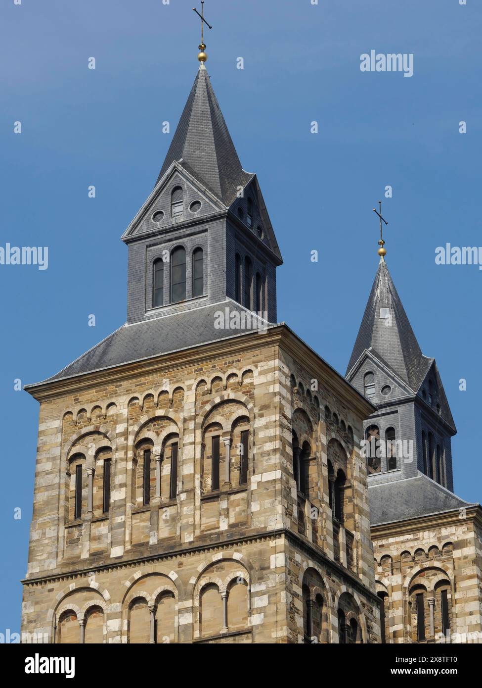 Two gothic stone towers of a cathedral silhouetted against a clear blue ...
