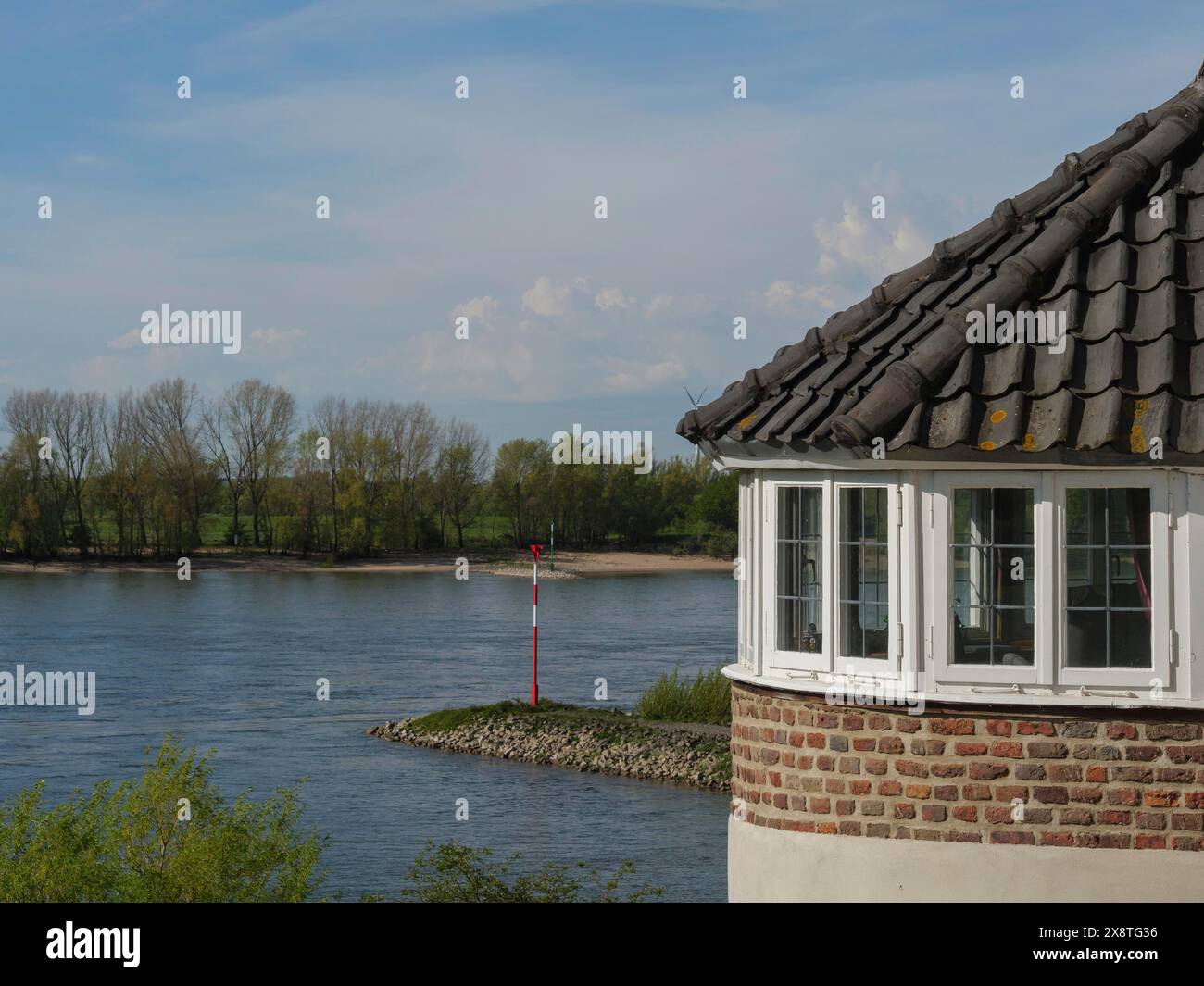 Partial view of a brick house with white windows on the riverbank ...