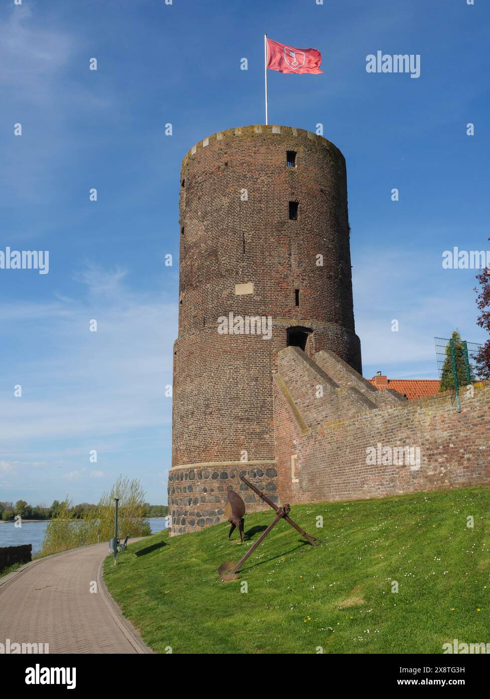 Medieval castle tower on a green hill with a flag under a clear blue ...