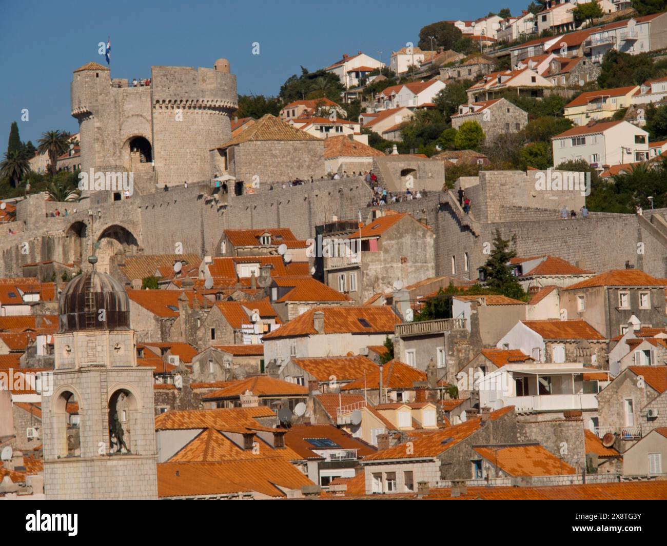 Historic city wall and fortress with orange-coloured roofs in a sunny ...