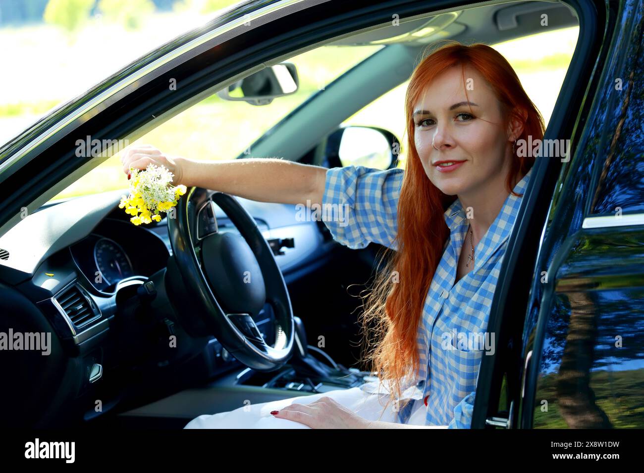 A girl poses for the camera with her car in nature. Joy, happiness ...