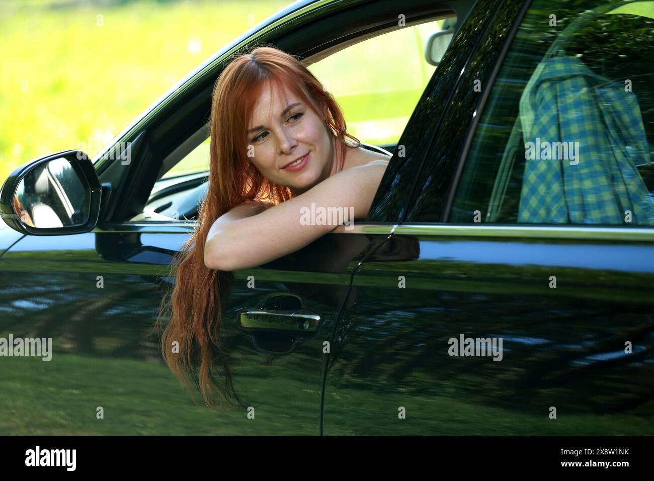 A girl poses for the camera with her car in nature. Joy, happiness ...