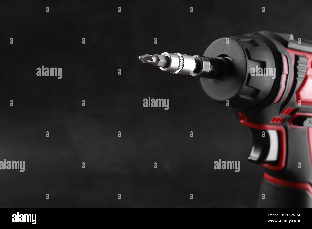 Modern electric screwdriver on dark grey background, closeup. Space for ...