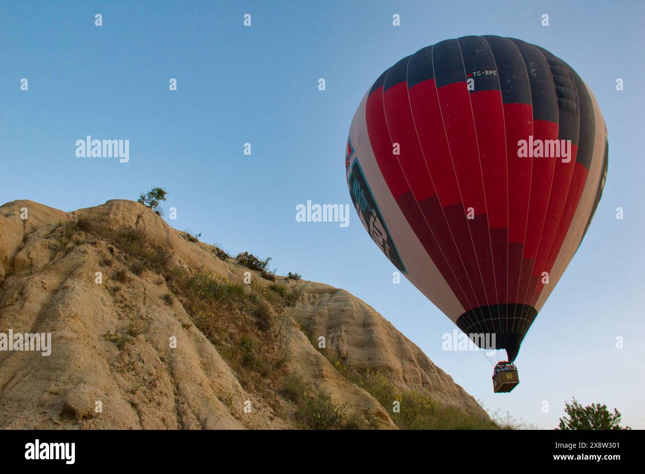 A striking hot air balloon glides above the rugged terrain of ...