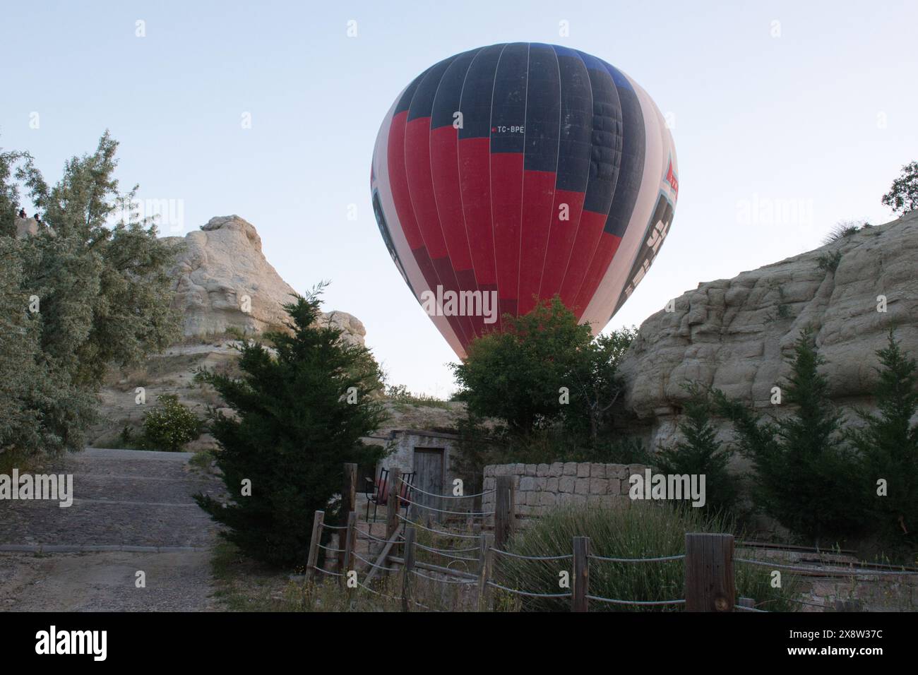 A striking hot air balloon glides above the rugged terrain of ...