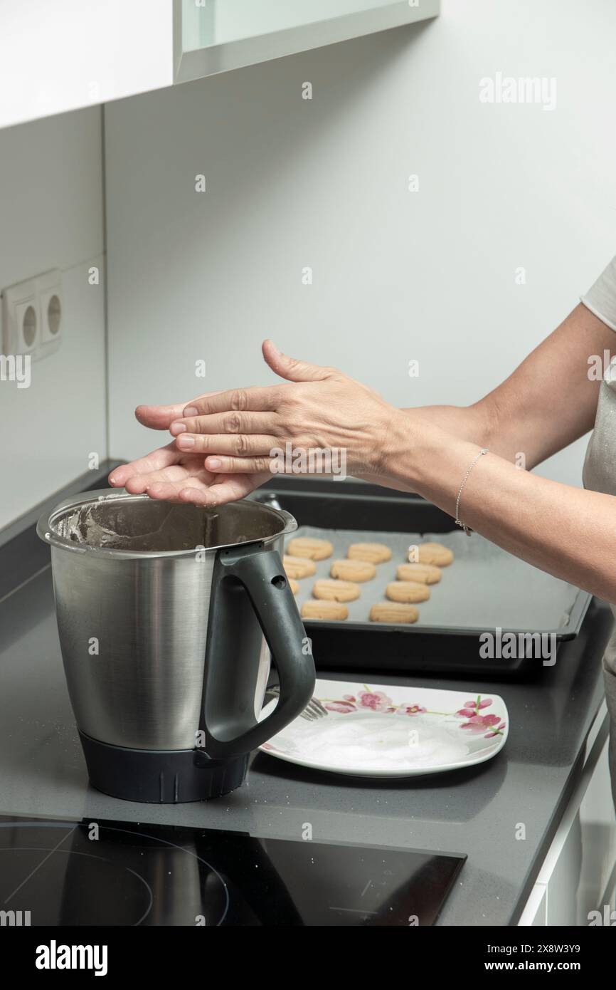 dusting flour over a kitchen blender with cookie dough, indicating ...