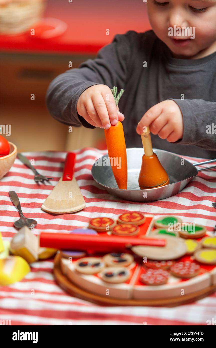 Toddler playing with wooden food at cooking. Imaginative play ...