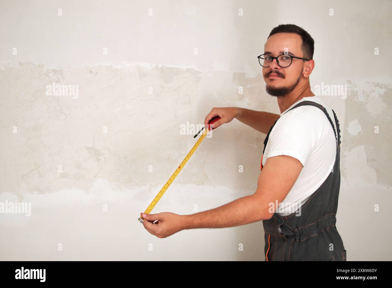 Young man with measuring tape on white background. Copy space. Smiling ...
