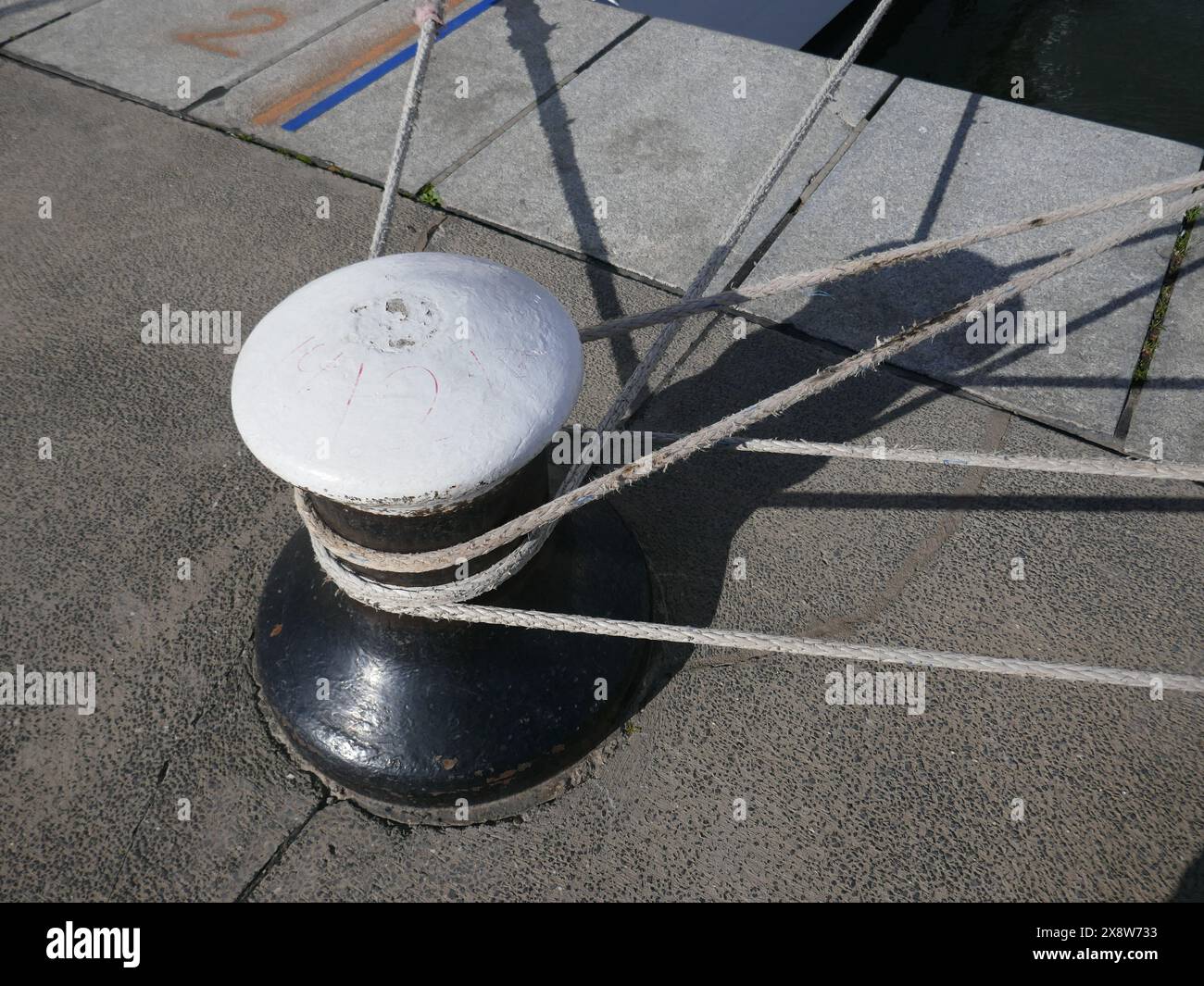Mooring bollard with mooring lines on concrete ship dock Stock Photo - Alamy