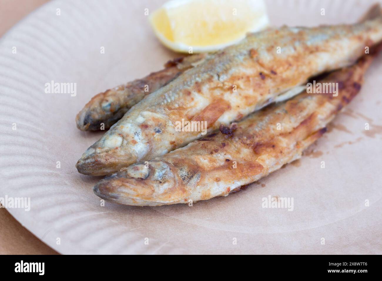 Delicious fried smelt on a cardboard plate with a slice of lemon, top ...