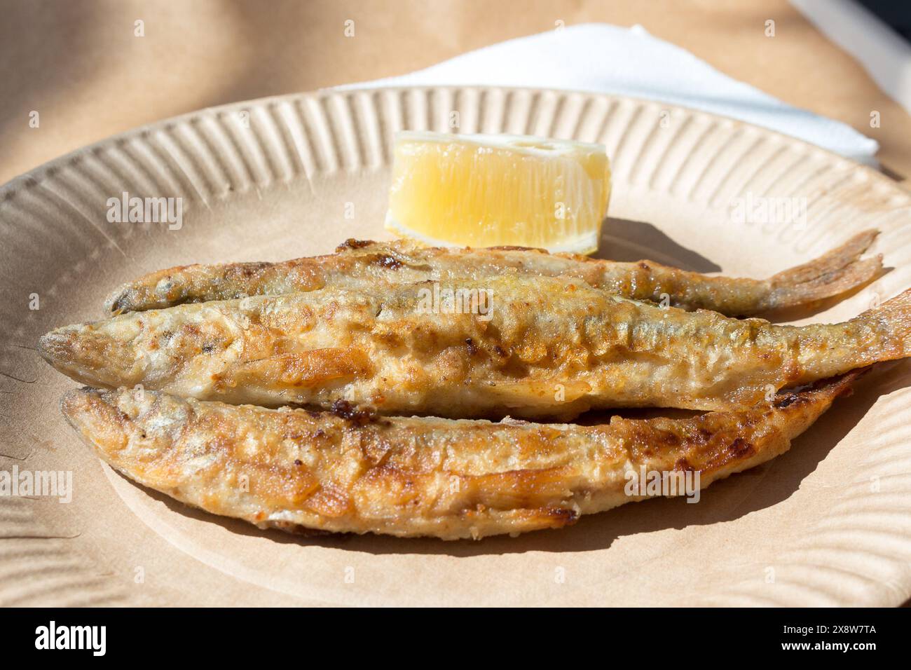 Delicious fried smelt on a cardboard plate with a slice of lemon, top ...