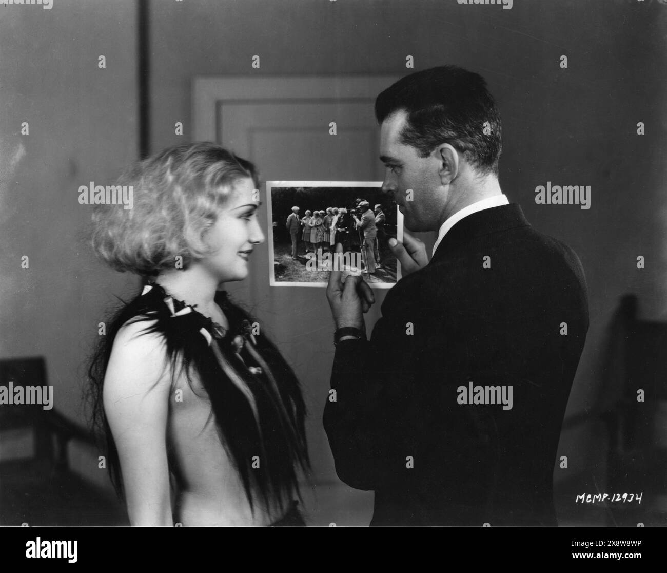 W.S. VAN DYKE and EDWINA BOOTH looking at a photo of the day when she ...