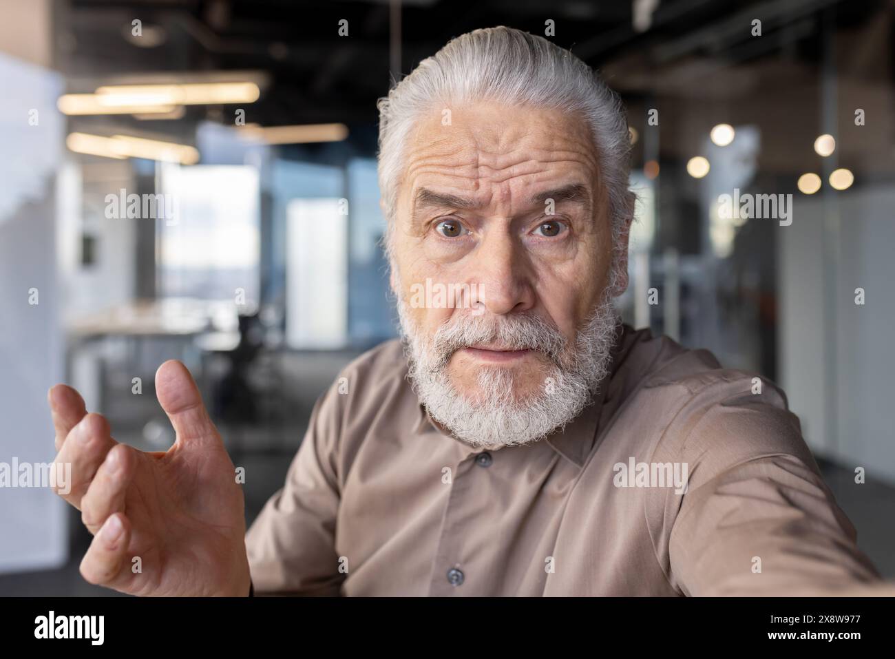 An elderly man with gray hair and beard looks surprised, gesturing ...