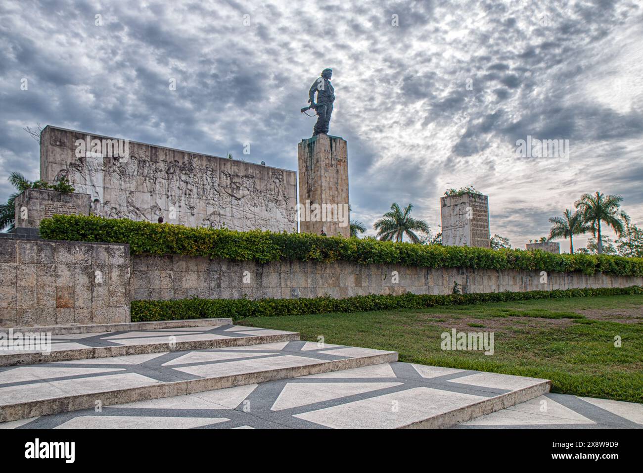 In the park stands a statue of a man atop a stone wall, surrounded by ...