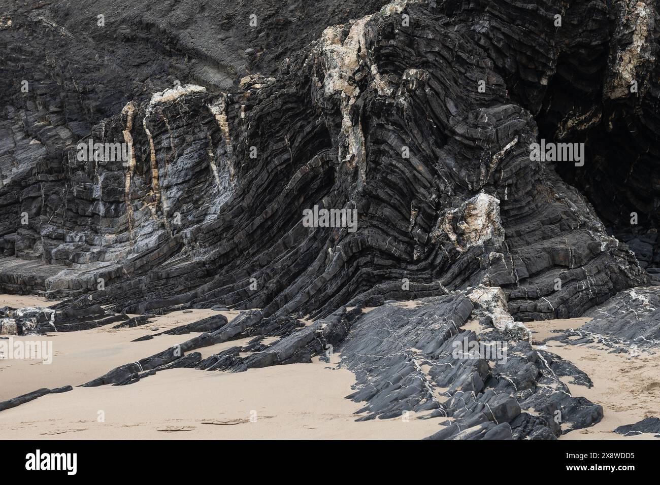 Close-up view of the unique black rock formations at Amoreira Beach ...