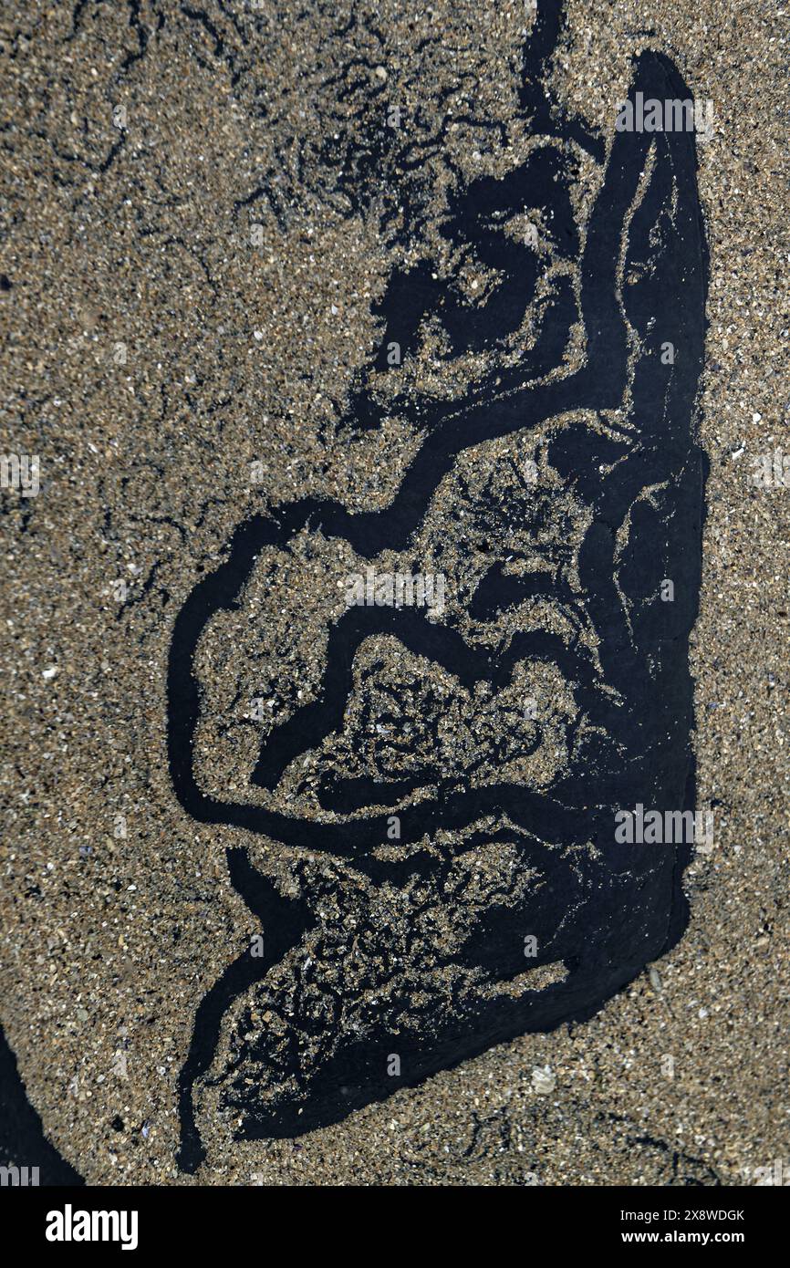 Close-up of intricate patterns formed by sand and black sediment on a ...