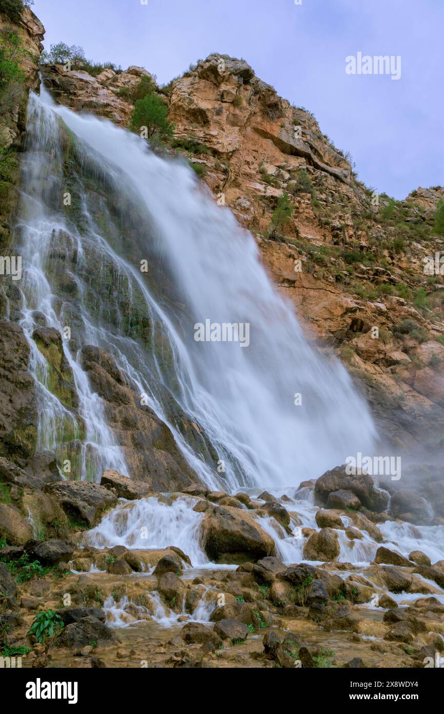 The image shows a powerful waterfall cascading down a rocky cliff Stock ...