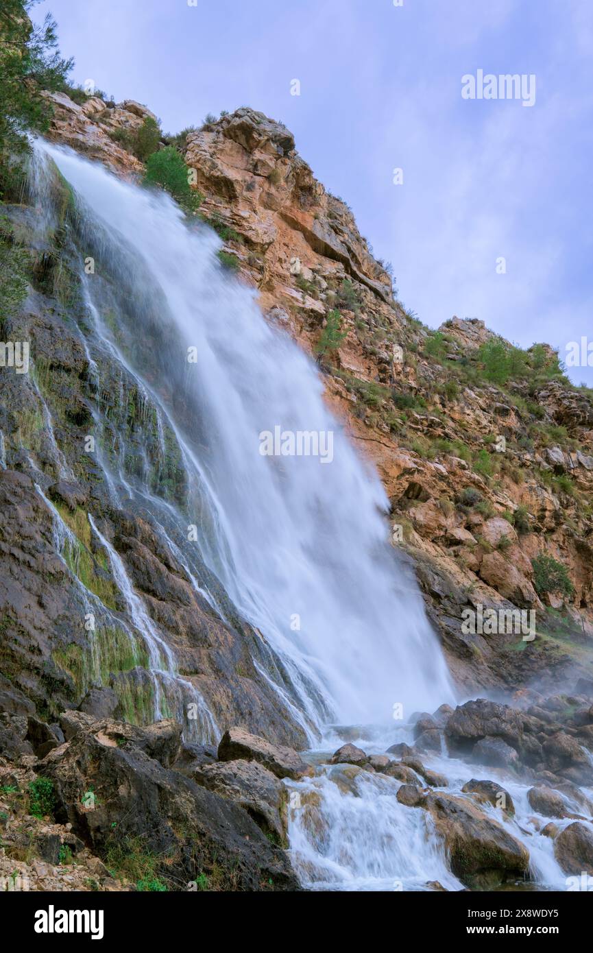 The image shows a powerful waterfall cascading down a rocky cliff Stock ...