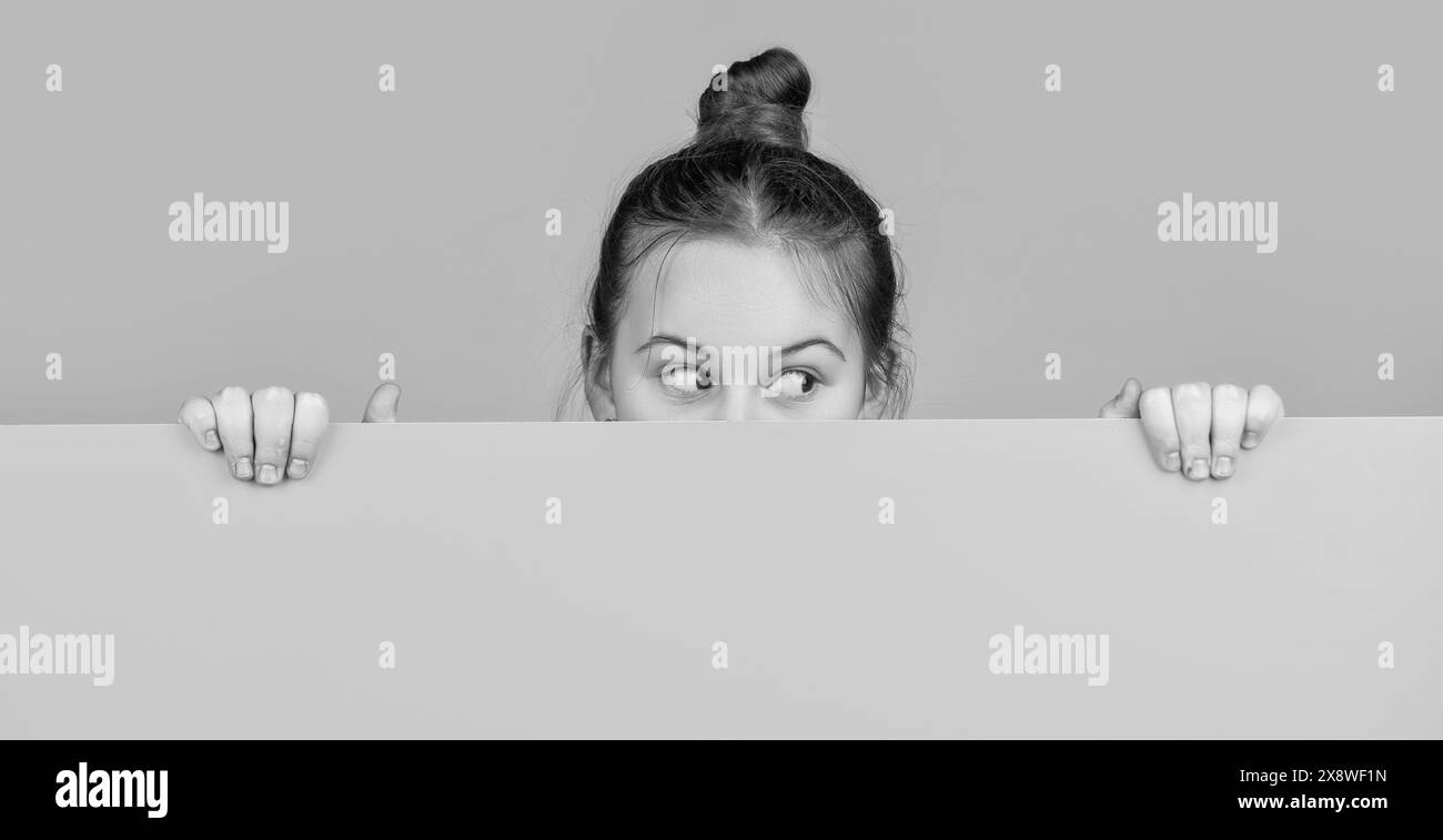 teen girl hiding behind blank yellow paper with copy space for ...