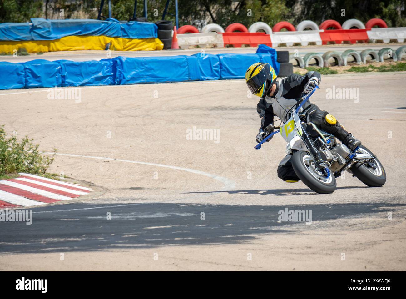 Motorcycle racer in protective gear takes a sharp corner on a sunny day ...
