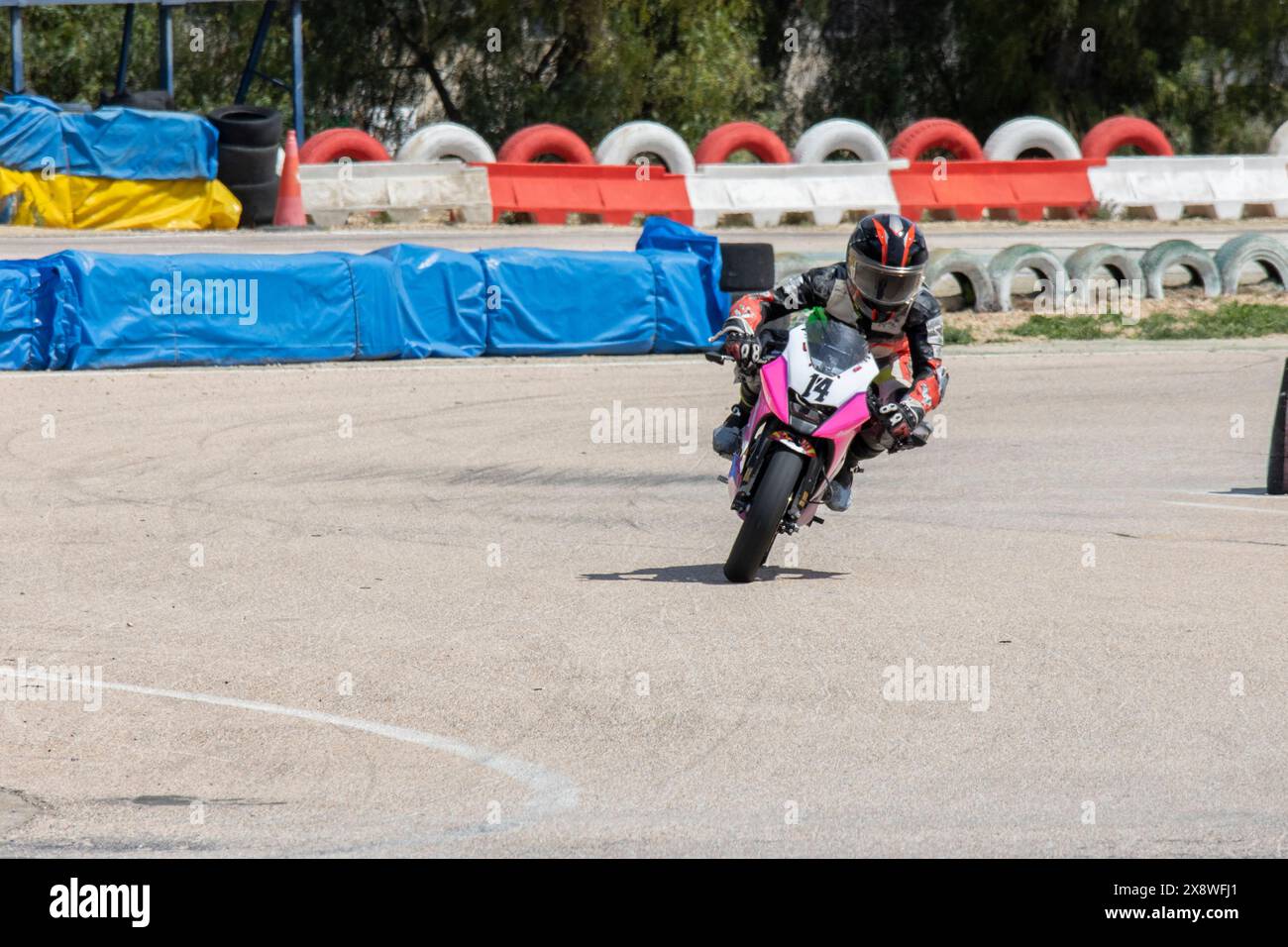 Motorcycle racer in full gear riding a pink bike takes a sharp turn on ...