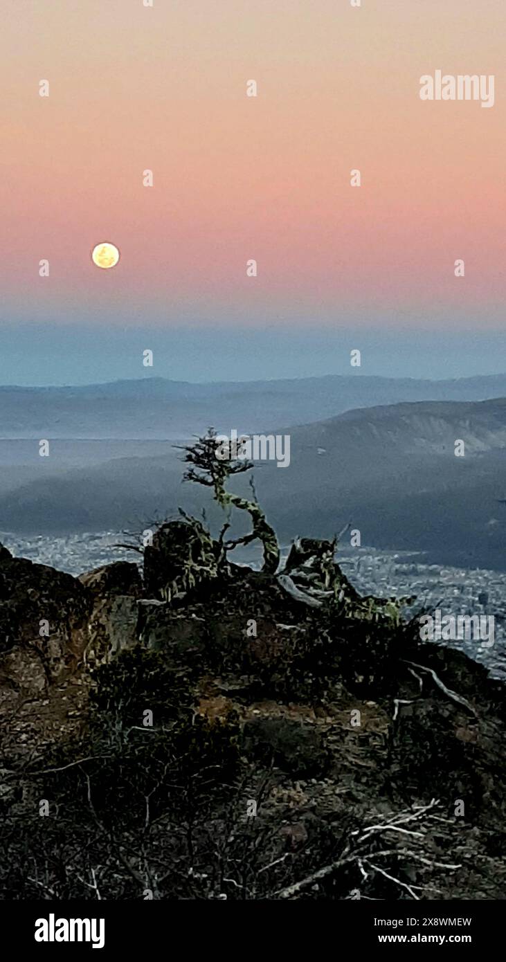 Full moon rising over a landscape with distant mountains, a colorful ...
