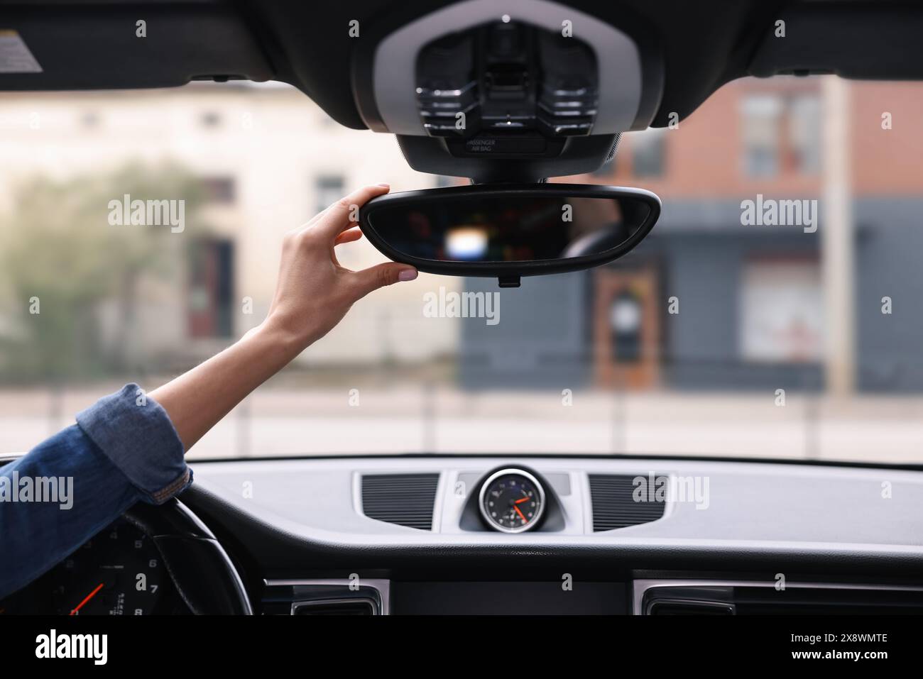 Woman adjusting rear view mirror inside her car, closeup Stock Photo ...