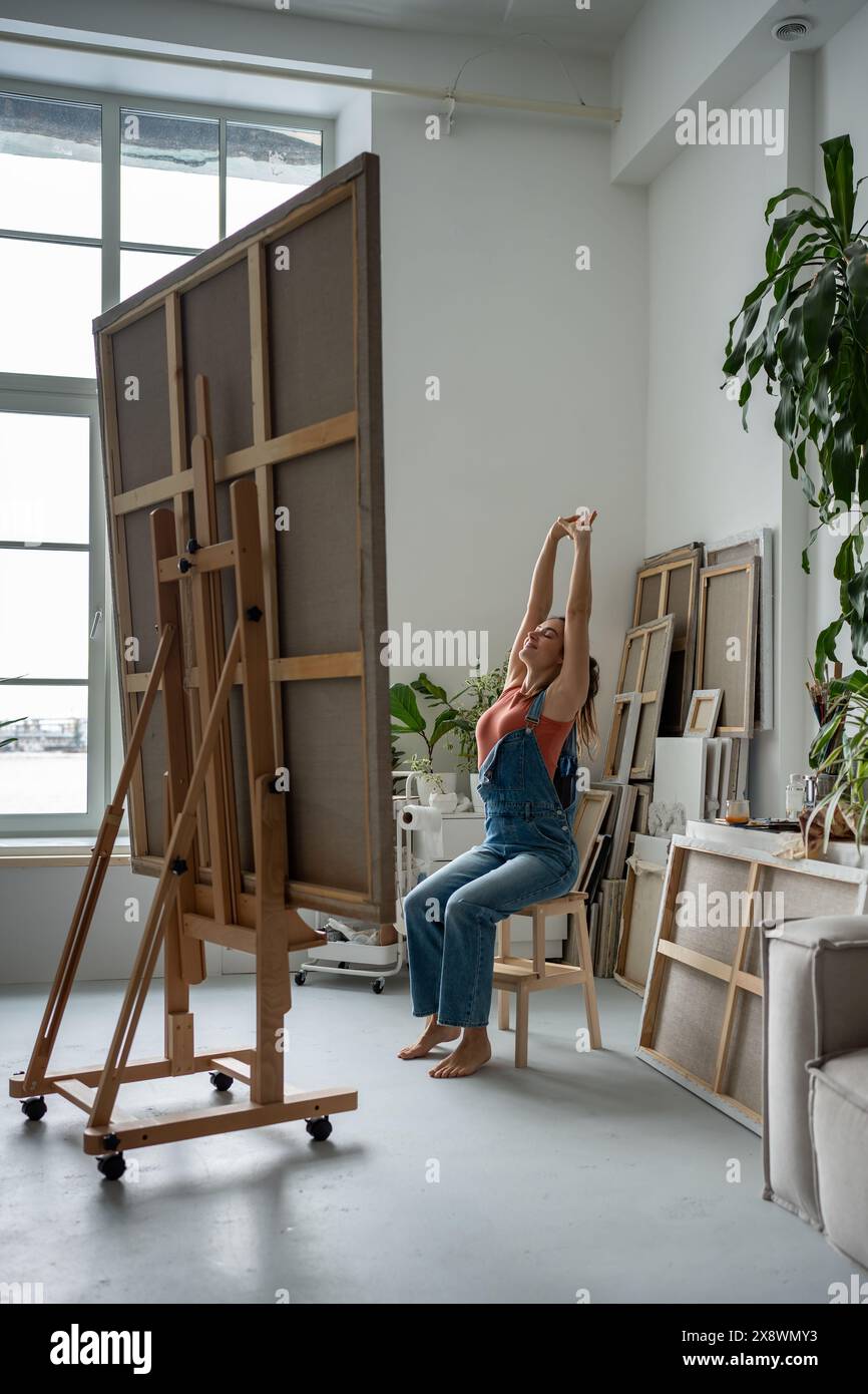Tired artist girl stretching hands relaxed from painting on canvas on ...