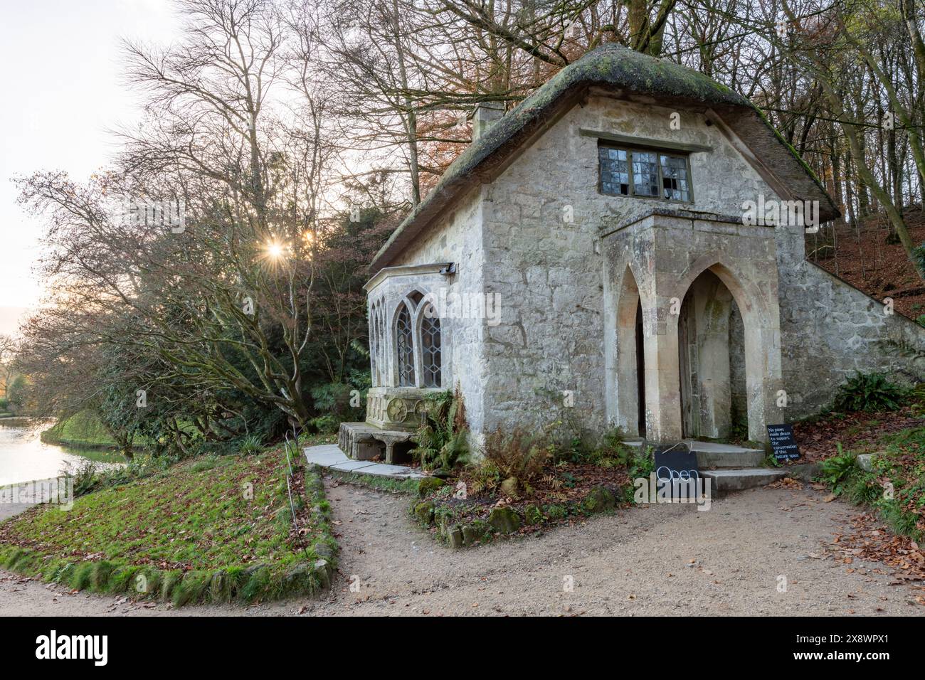 The sun setting behind the Gothic Cottage at Stourhead Gardens in ...