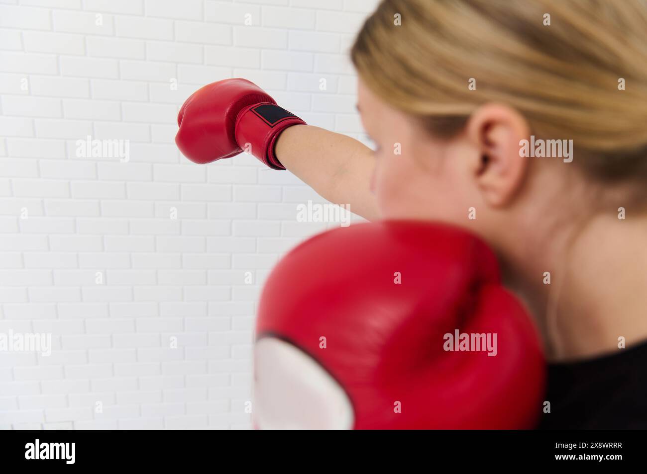 Close-up rear view of young blond woman fighter, determined boxer ...