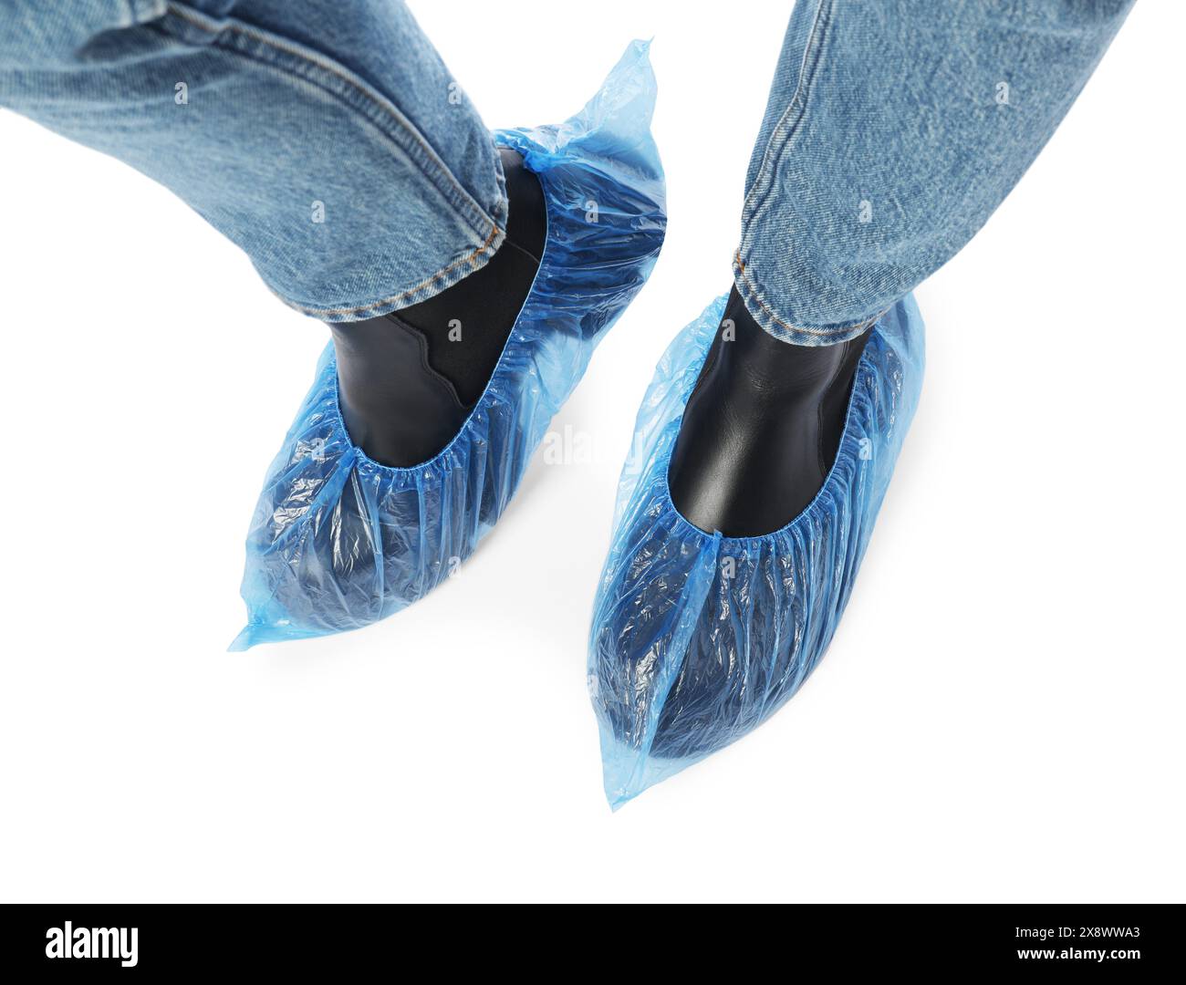 Woman wearing blue shoe covers onto her boots against white background ...