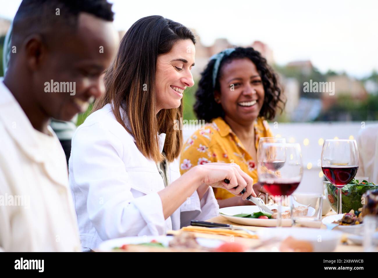 Side view of smiling Caucasian woman eating food sitting at table with ...