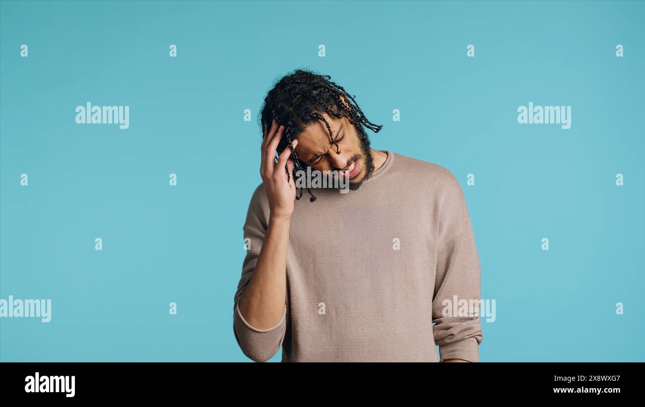 Hurt Middle Eastern man wincing from pain, suffering from headache ...