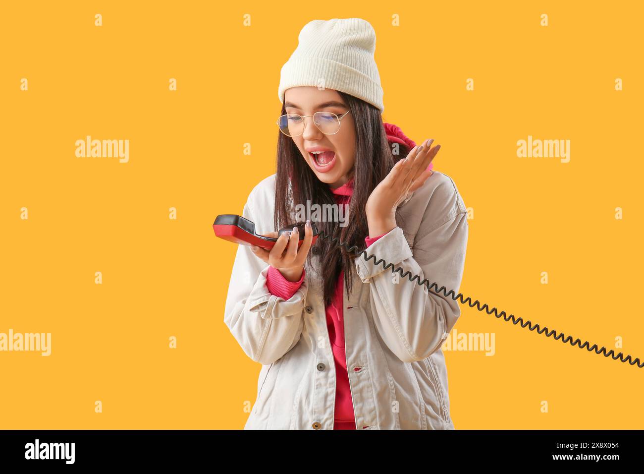 Screaming young woman with telephone receiver on yellow background ...
