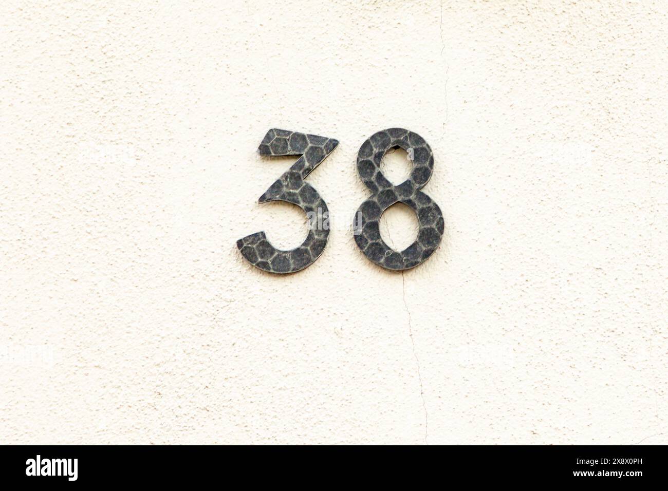 house number 38 in metal at white painted plaster wall in vintage style ...