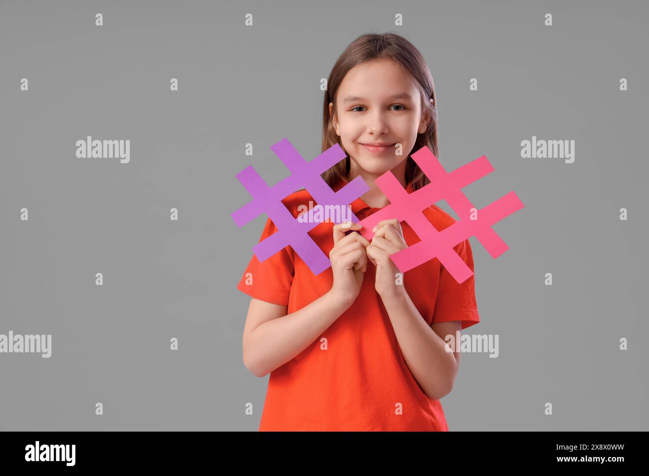 Cute teenage girl with hashtags on grey background Stock Photo - Alamy