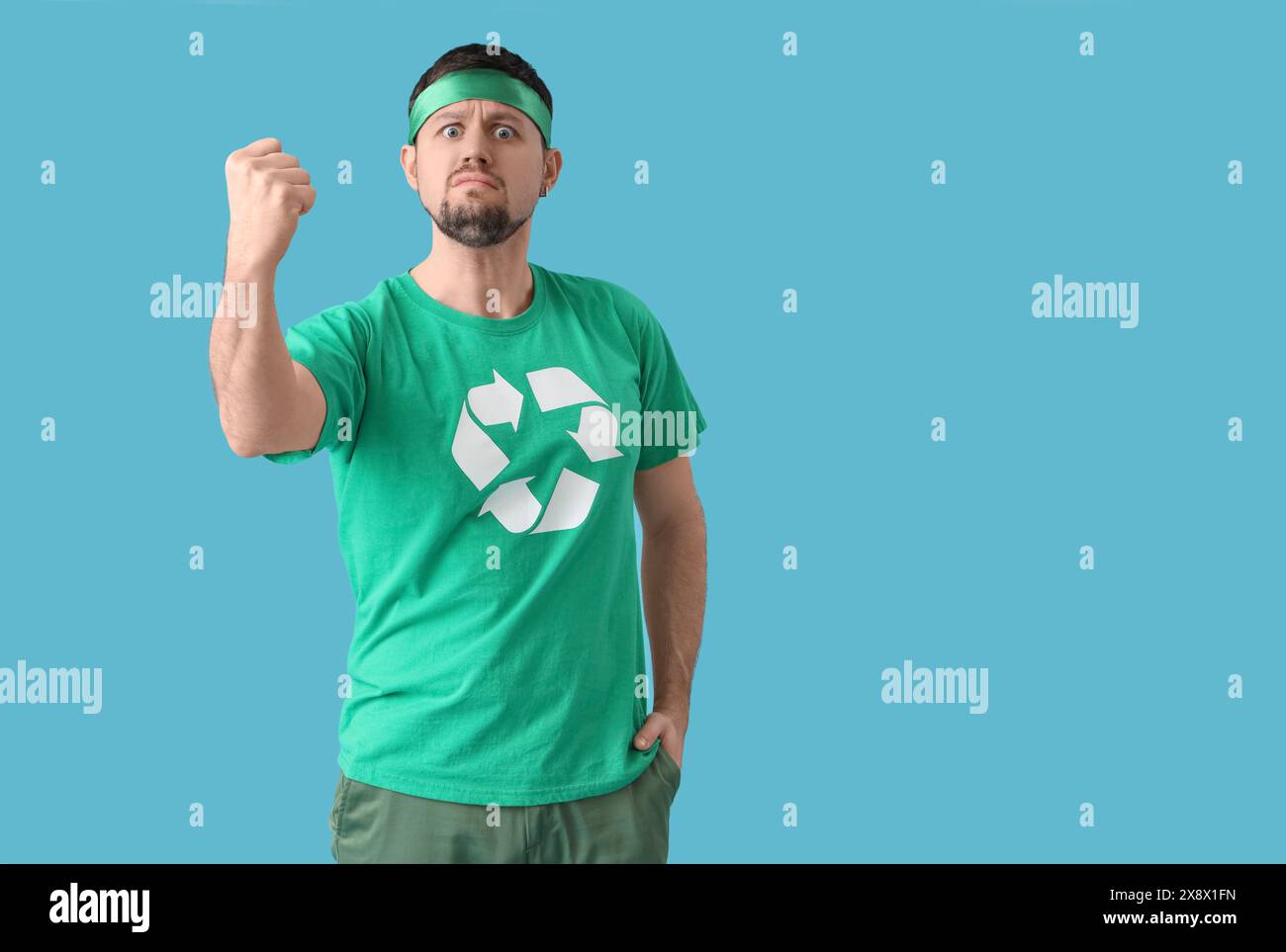 Angry young man in t-shirt with recycling logo shaking fist on blue ...
