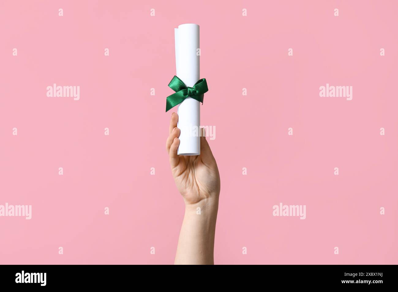 Female hand holding diploma with ribbon on pink background Stock Photo ...