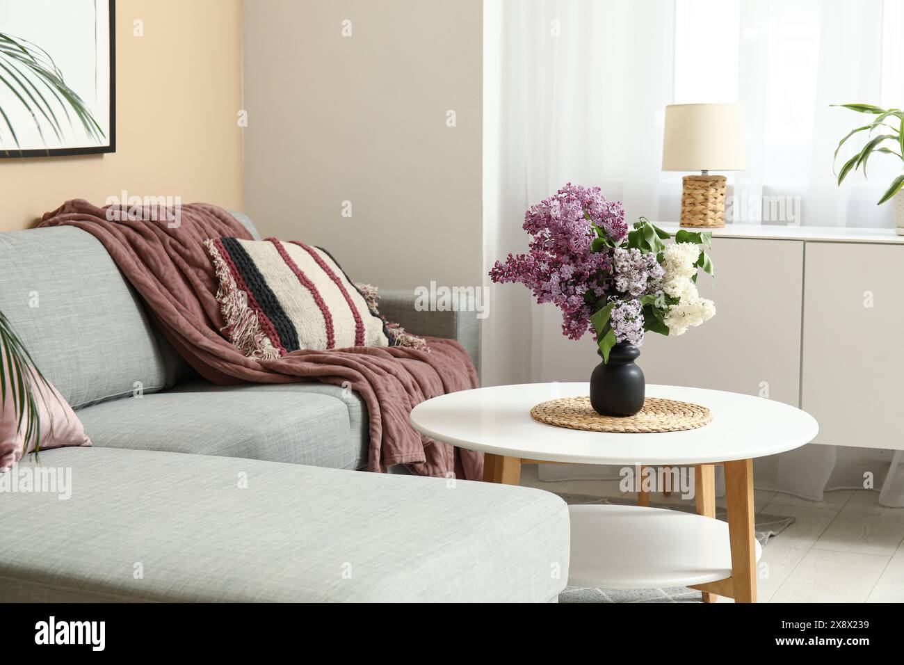 Beautiful living room with bouquet of lilacs branches on coffee table ...